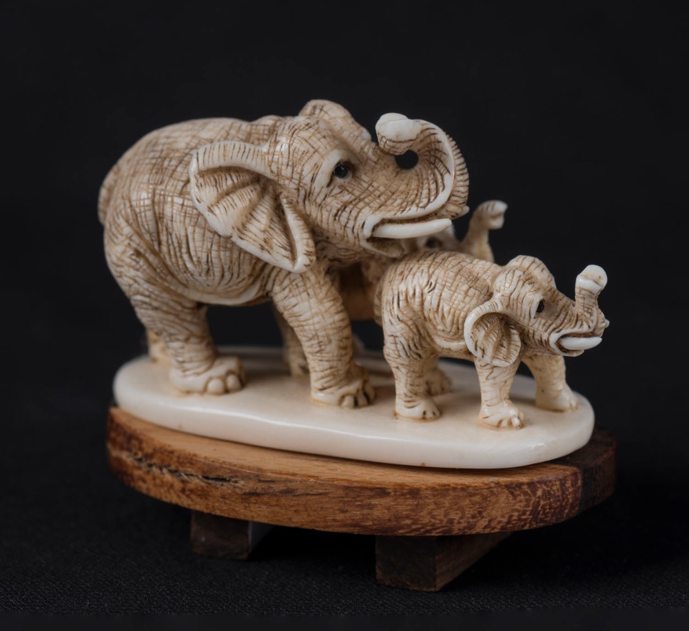 A Japanese carved ivory elephant group netsuke, on later wooden base ...