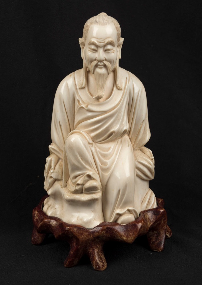 A Chinese carved ivory statue of a seated scholar, with carved wooden ...