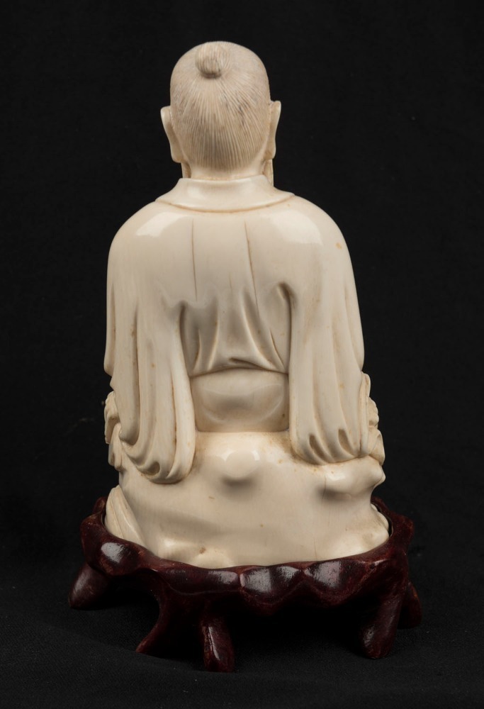 A Chinese carved ivory statue of a seated scholar, with carved wooden ...