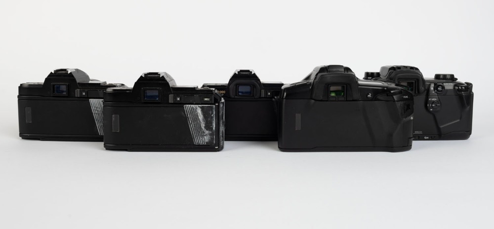 MINOLTA: Five black SLR camera bodies, one with lens and the others ...