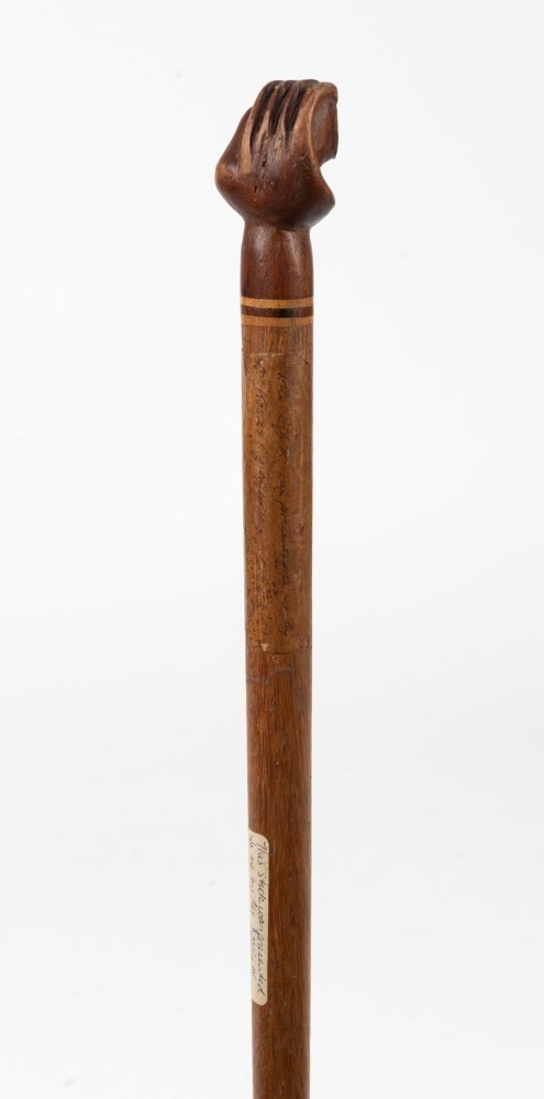 A Pitcairn Island palmwood walking stick with clenched fist handle. A ...