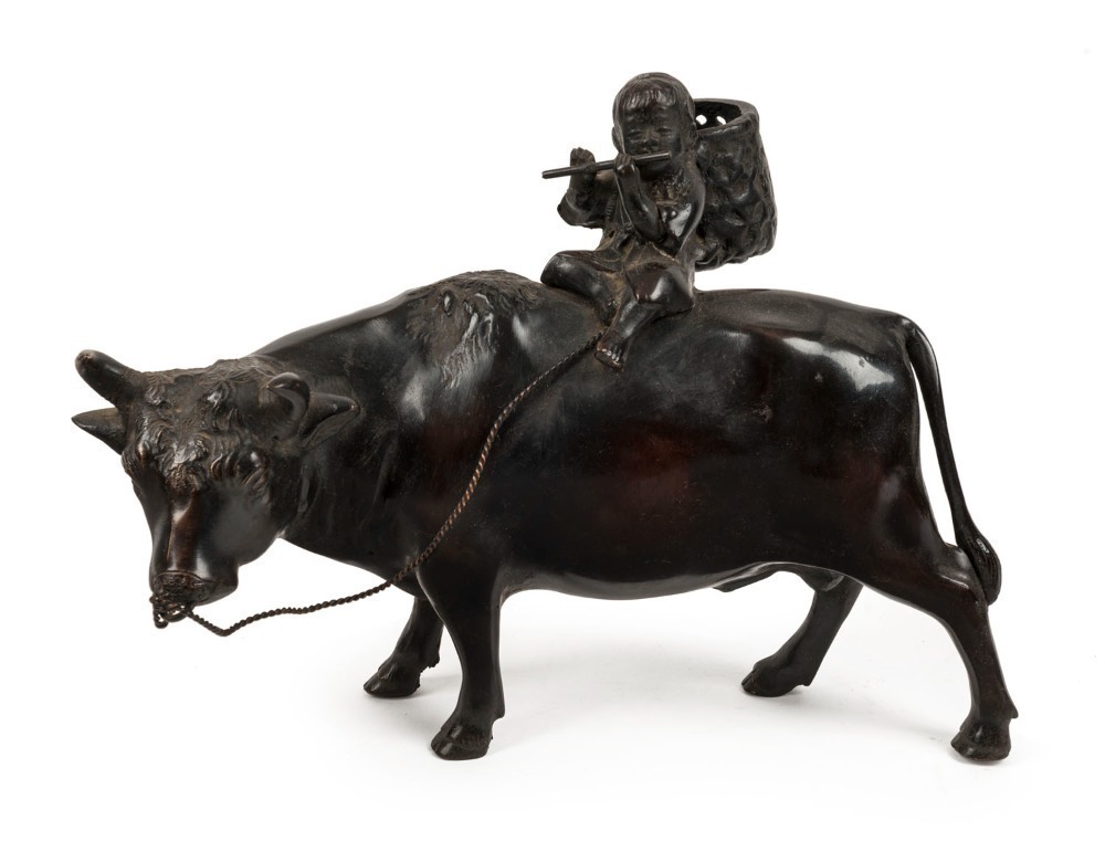 A Chinese cast bronze statue of a boy with flute sitting on an ox, 19th ...